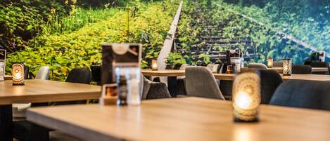 Um restaurante com mesas e cadeiras de madeira, um suporte para cardápio e castiçais decorativos.