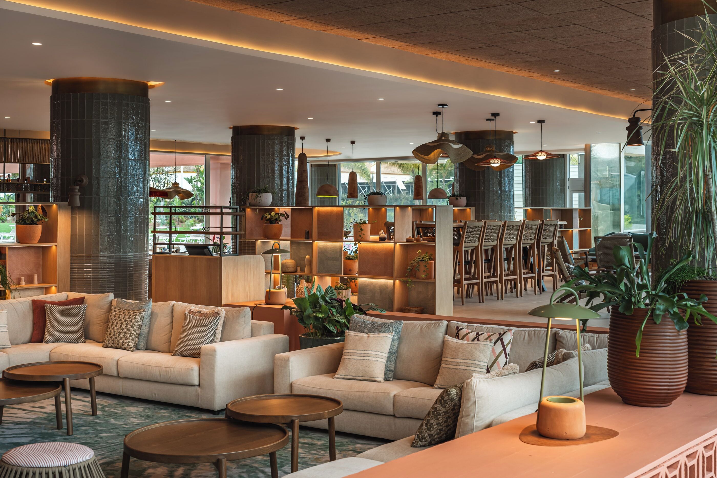 Um hall de hotel moderno com sofás, mesas e plantas em vasos.