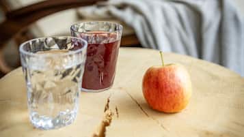 Uma mesa de madeira com dois copos de água e um copo de suco, e uma maçã sobre a superfície de madeira.