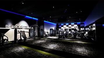 Uma academia com diversos equipamentos de exercício, uma parede xadrez e o nome 'BLACK GYM' na parede.