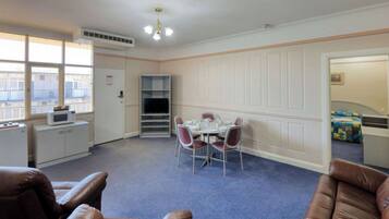 Quarto de hotel com área de refeições, cozinha compacta e vista para a cidade.