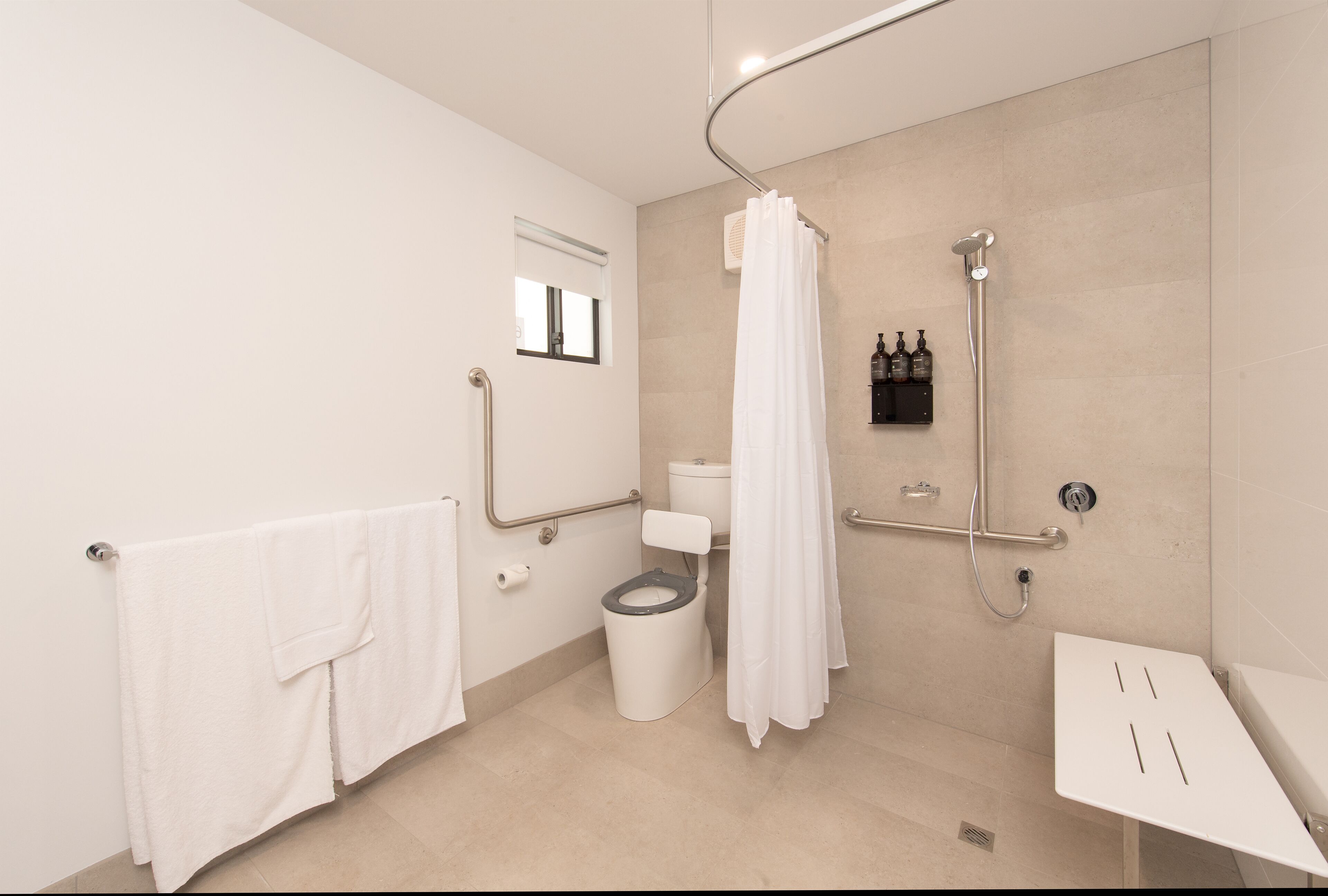 Uma casa de banho moderna com sanita, chuveiro e lavatório.