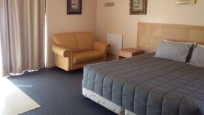 Quarto de hotel com cama, cadeira, mesa de cabeceira e ar-condicionado fixado na parede.