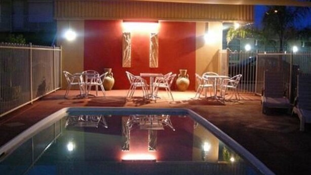 Uma área de piscina ao ar livre com design moderno, incluindo piscina, cadeiras e mesas.