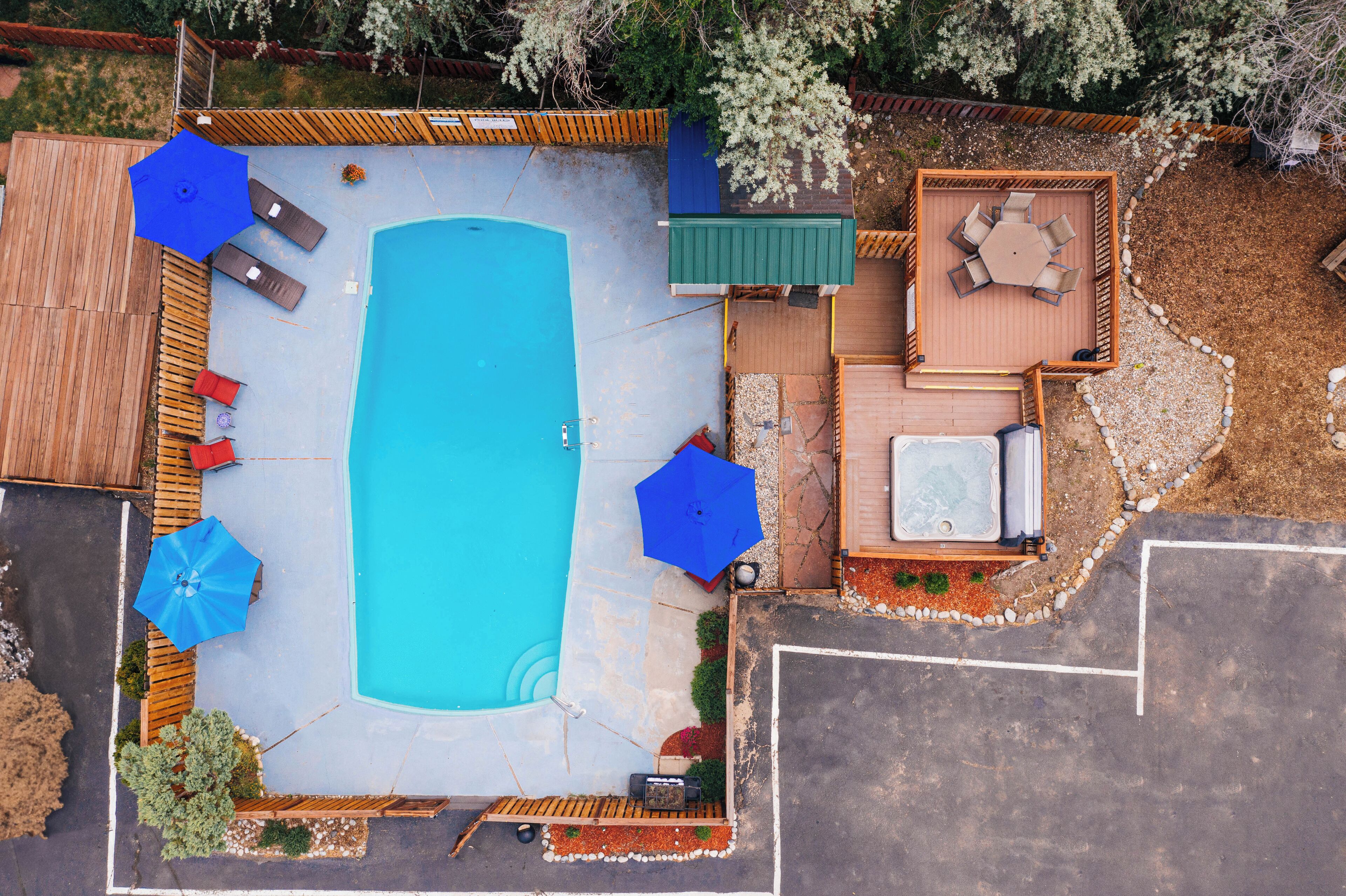 Piscina retangular rodeada por um deck de madeira, com espreguiçadeiras e guarda-sóis.
