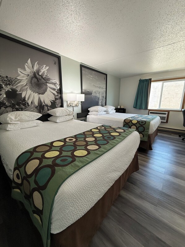 Quarto de hotel com duas camas, um mural grande na parede, uma janela com cortinas e um ar-condicionado fixado na parede.