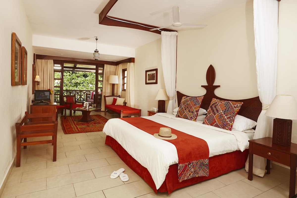 Quarto de hotel com cama grande, uma escrivaninha, uma cadeira e vista para o exterior.