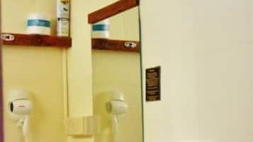 Casa de banho com espelho, lavatório, toalheiro e secador de cabelo.