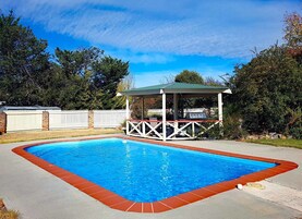 Piscina retangular com borda revestida em azulejo, rodeada por um deck de concreto.