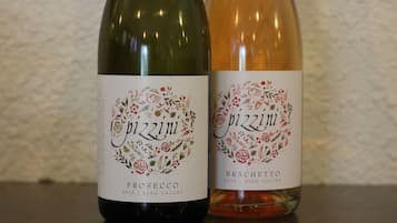 Duas garrafas de vinho, uma com o rótulo 'PROSECCO' e outra com 'BRACCHETTO', ambas da marca 'Pizzini' e da região 'King Valley'.