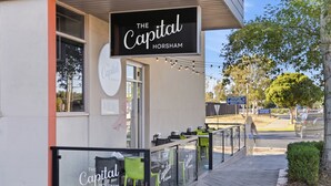 Restaurante chamado 'The Capital Horsham' com área externa para refeições e uma placa indicando atrações próximas.
