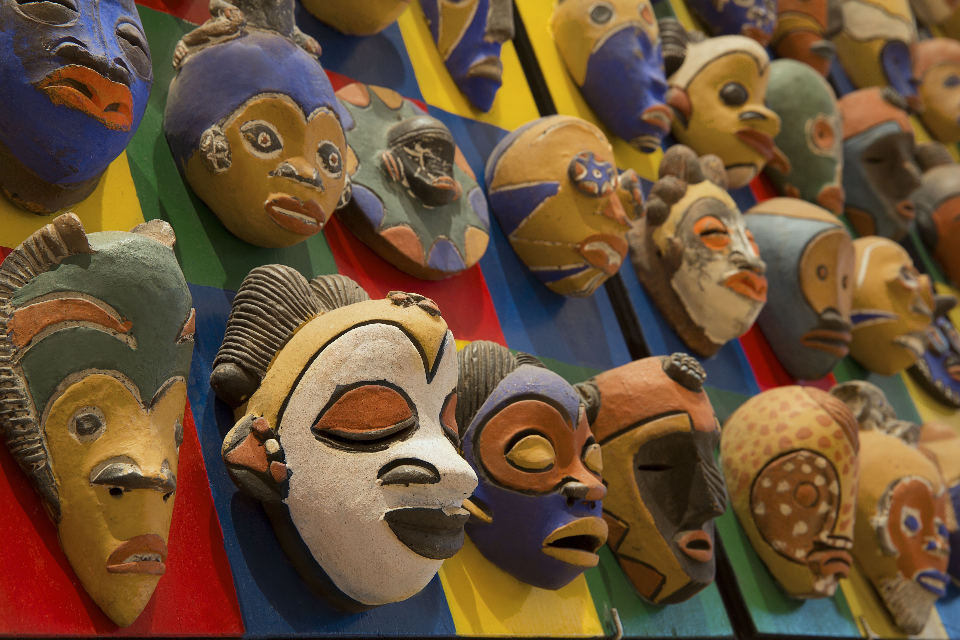Uma coleção de máscaras coloridas expostas em uma parede.