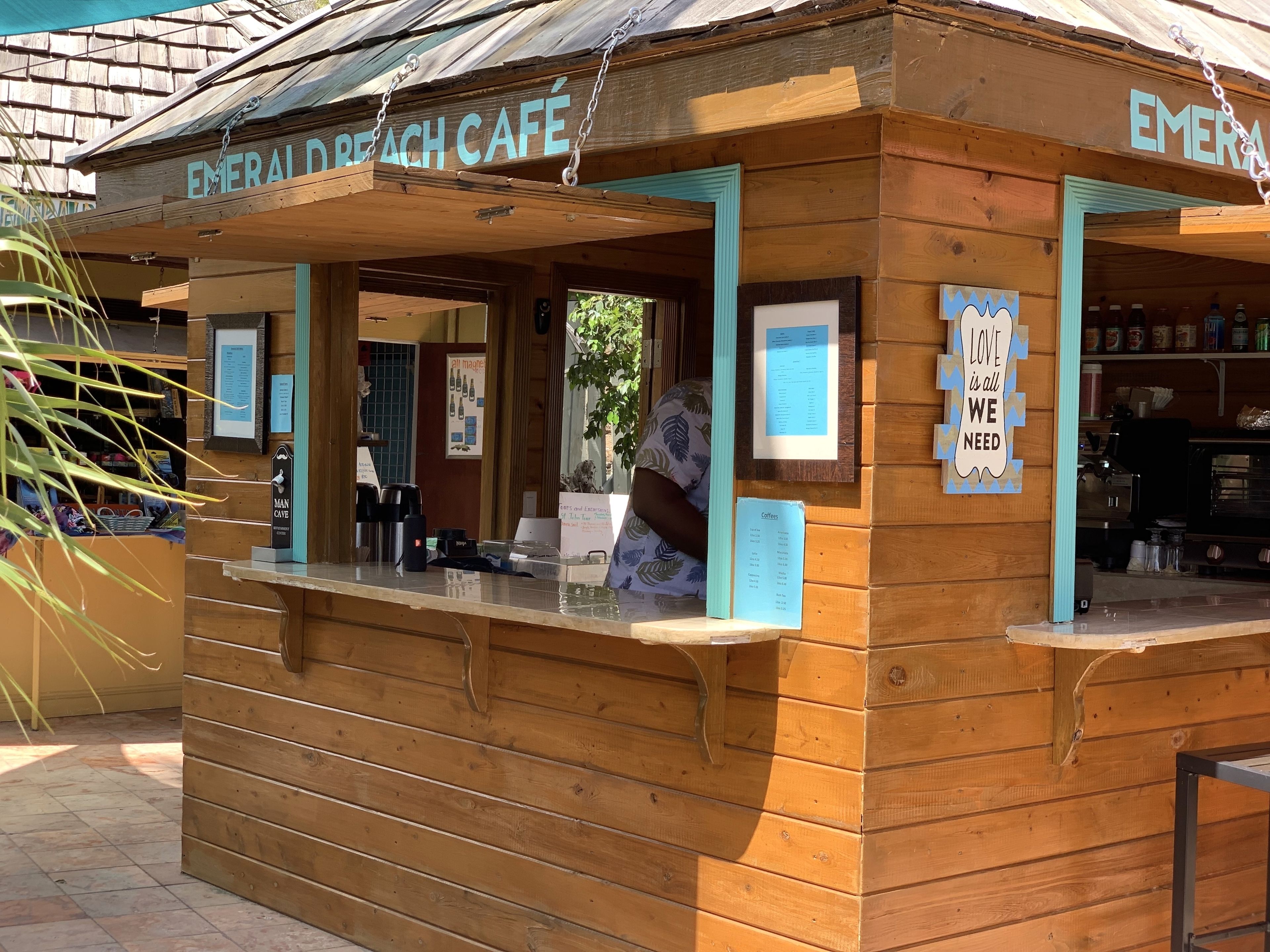 Um café à beira-mar de madeira com uma placa que diz 'EMERALD BEACH CAFE'.