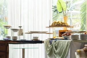 Disposição de buffet com diversos pratos e uma planta decorativa.