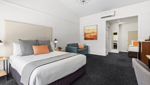 Quarto de hotel moderno com uma cama grande, uma escrivaninha, uma cadeira e um quadro na parede.