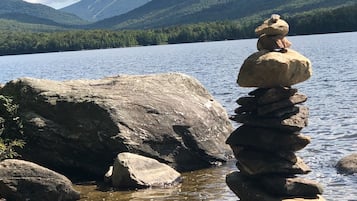 Uma pilha de pedras à beira de um lago, com montanhas ao fundo.