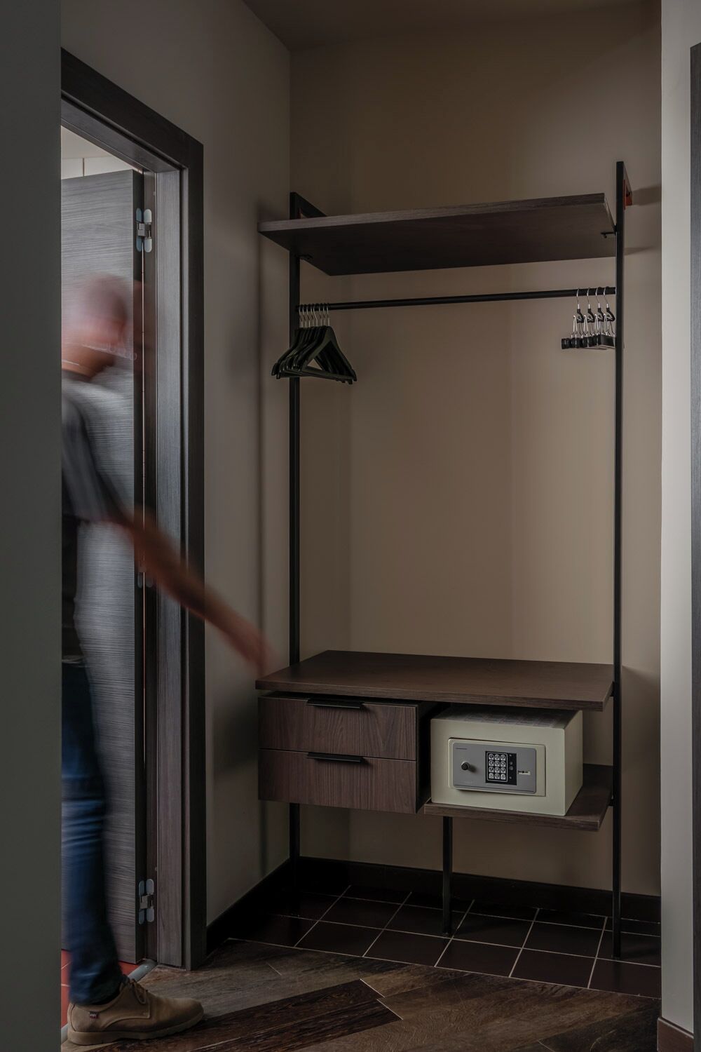 Uma cama beliche com escrivaninha e cofre, uma porta com puxador e piso cerâmico.
