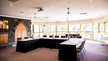 Uma sala de conferências com uma mesa comprida, cadeiras, um quadro branco e uma parede de pedra.