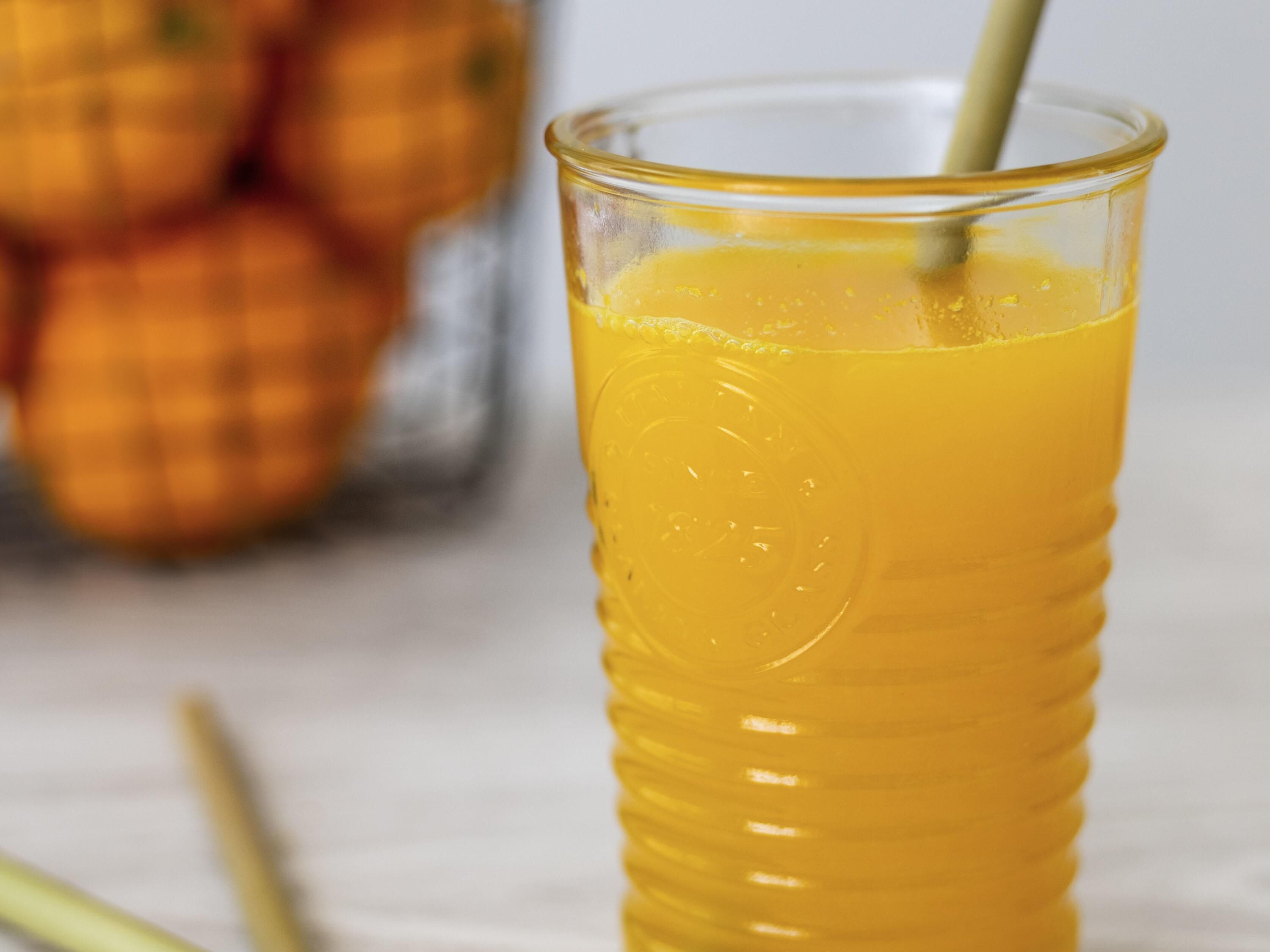 Um copo de suco de laranja com canudo.