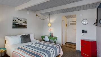 Quarto com cama, escrivaninha, armário vermelho e um quadro na parede.