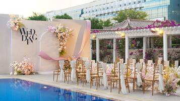 Decoração de recepção de casamento com piscina, flores e um pavilhão.