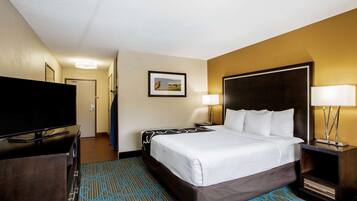 Quarto de hotel com uma cama grande, uma televisão de tela plana, uma escrivaninha e uma luminária.