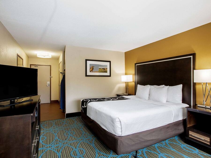 Quarto de hotel com uma cama grande, uma televisão de tela plana, uma escrivaninha e uma luminária.