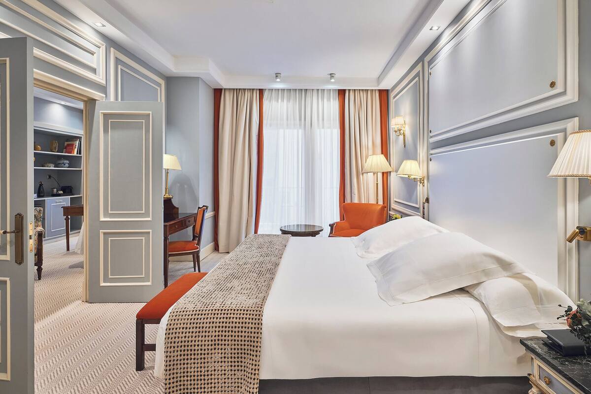 Quarto de hotel com uma cama grande, uma escrivaninha, uma cadeira e um guarda-roupa.