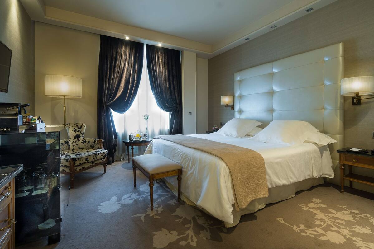 Quarto de hotel com uma cama grande, uma mesa, uma cadeira e uma televisão.
