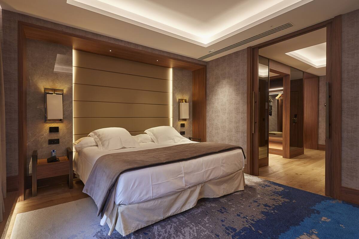 Quarto de hotel moderno com uma cama grande, mesas de cabeceira e um closet espaçoso.