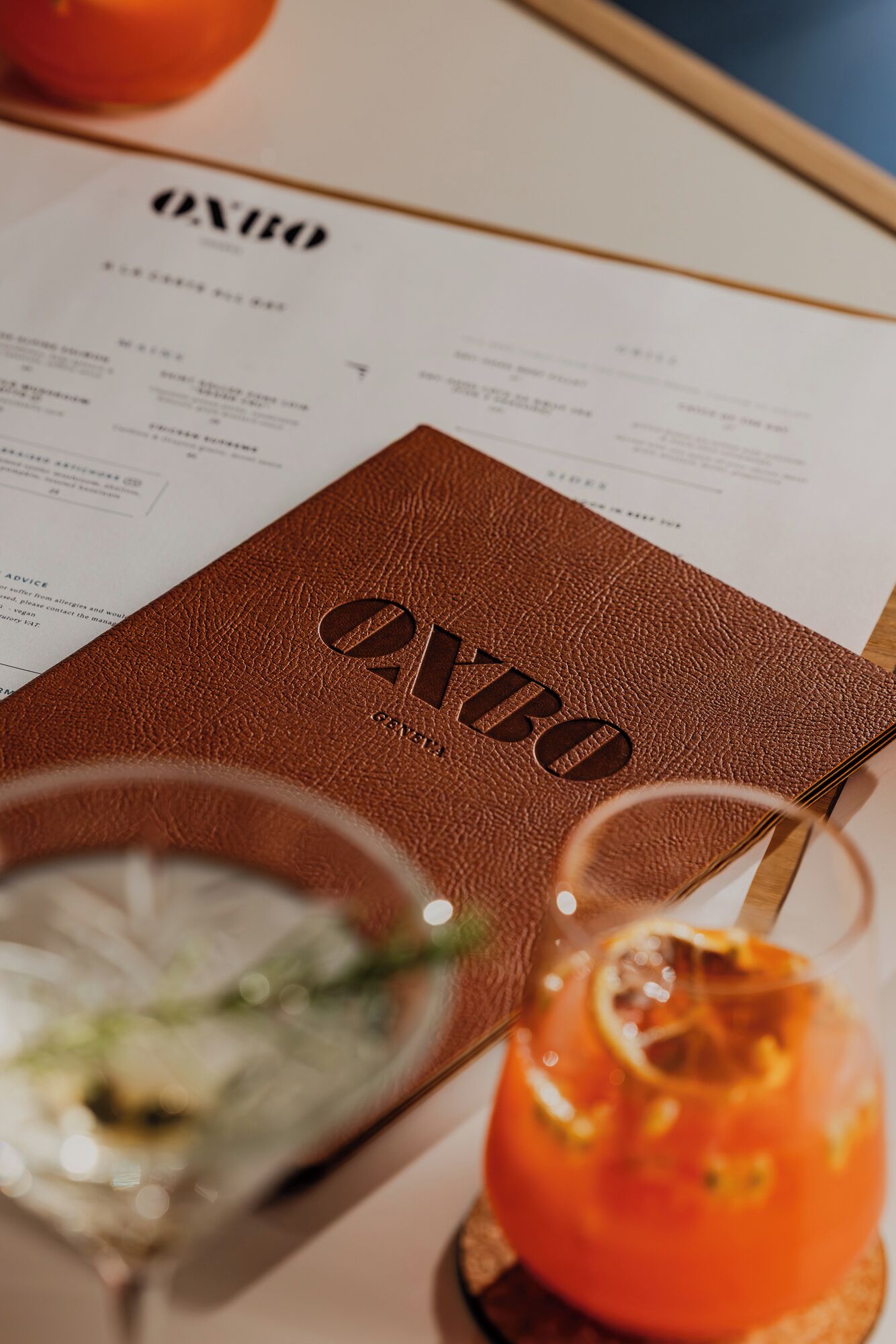 Um menu, um caderno de couro marrom e um copo com bebida.