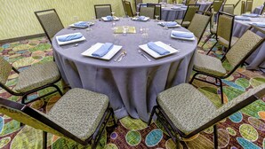 Sala de conferência com mesa redonda, cadeiras e piso coberto por carpete.