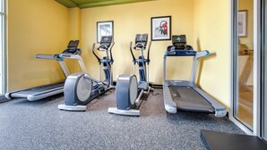 Sala de ginástica com três esteiras, uma bicicleta ergométrica e um aparelho de exercício fixado na parede.