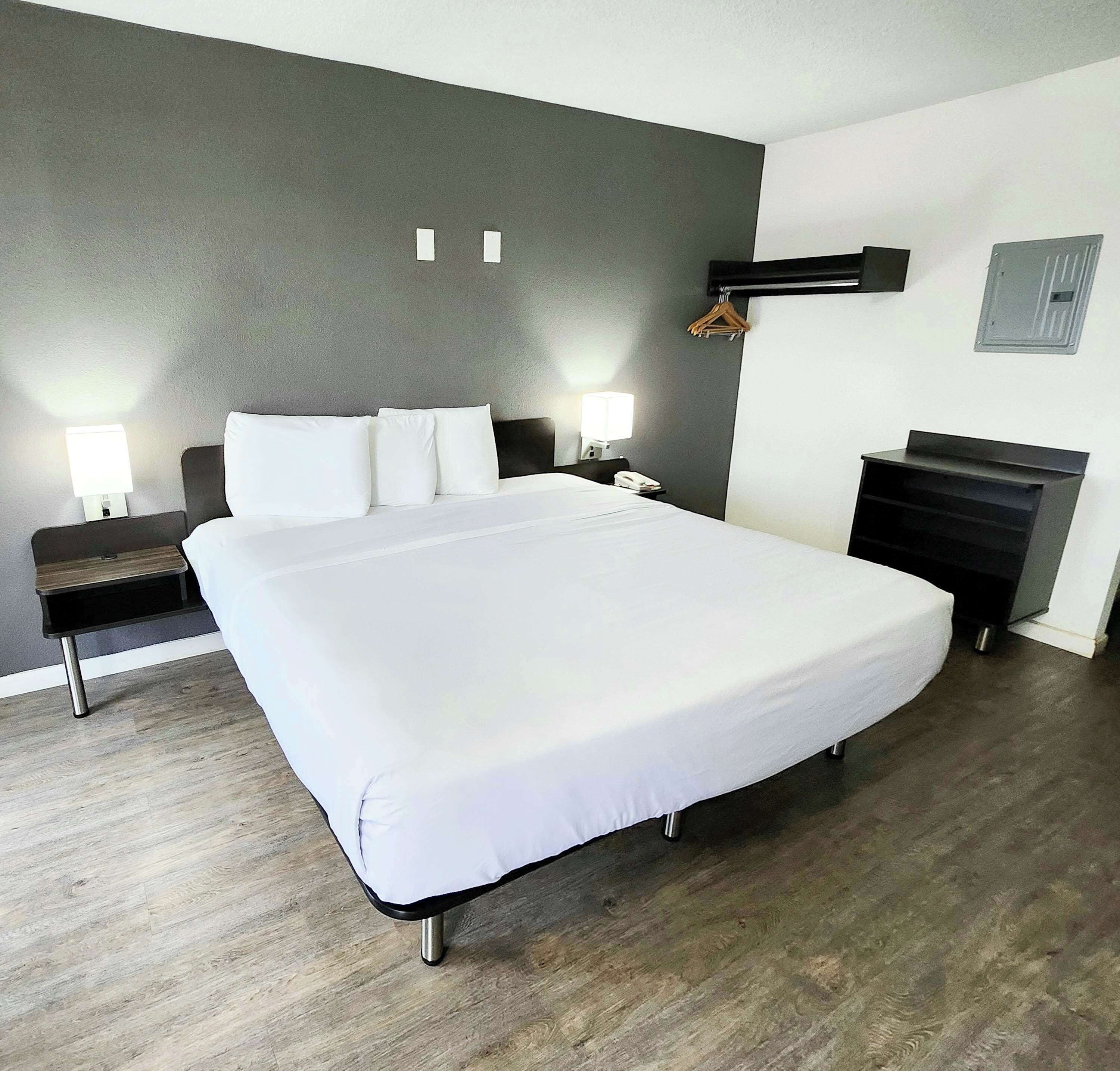 Quarto de hotel moderno com uma cama grande, mesas de cabeceira, um guarda-roupa e um aquecedor fixado na parede.