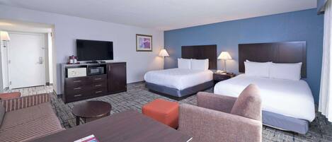 Quarto de hotel com duas camas, televisão, escrivaninha e uma cadeira.