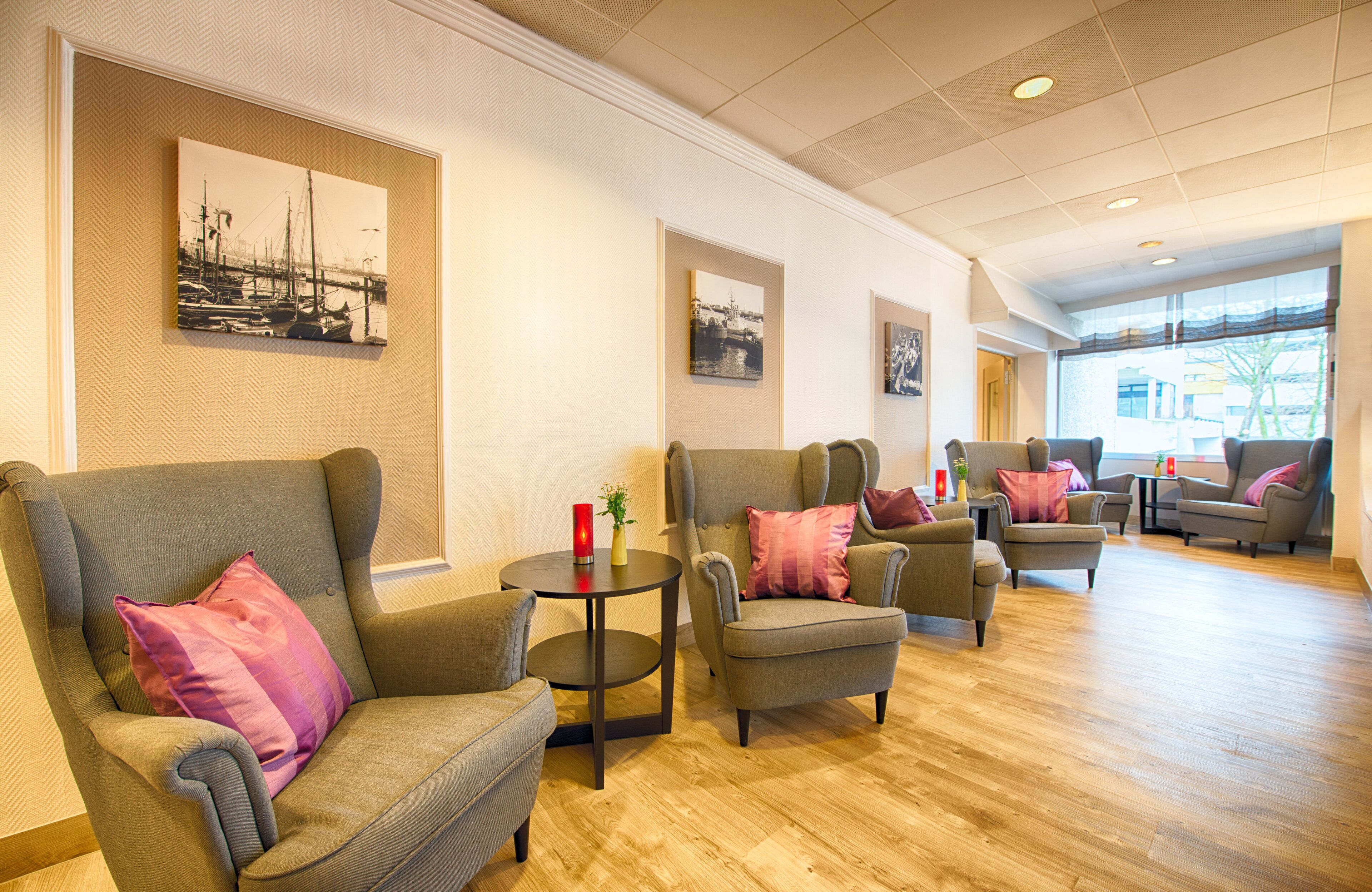 Um hall de hotel com várias áreas de estar, piso de madeira e obras de arte fixadas na parede.