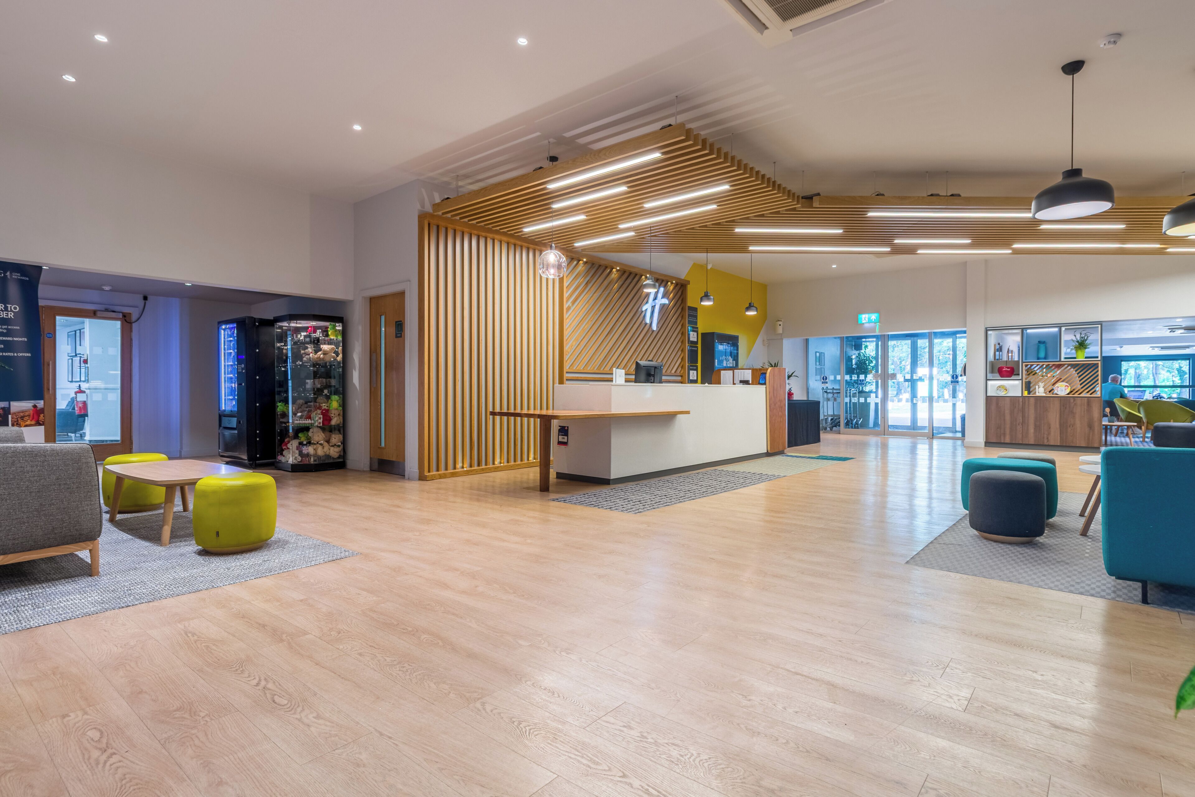 Uma área de recepção moderna com painel de madeira em ripas, balcão de atendimento e espaços de estar.