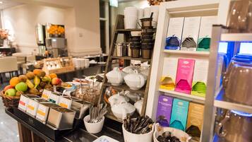 Uma área de buffet com diversos alimentos, utensílios e dispensadores de bebidas.