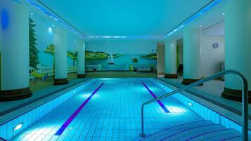 Uma piscina com chão de azulejos, um mural na parede retratando uma paisagem e um relógio na parede.