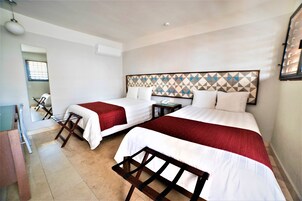 Quarto de hotel com duas camas, uma escrivaninha e uma cadeira.