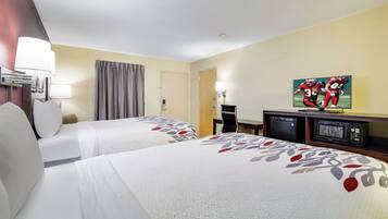 Quarto de hotel com duas camas, televisão, secretária com micro-ondas e uma porta.