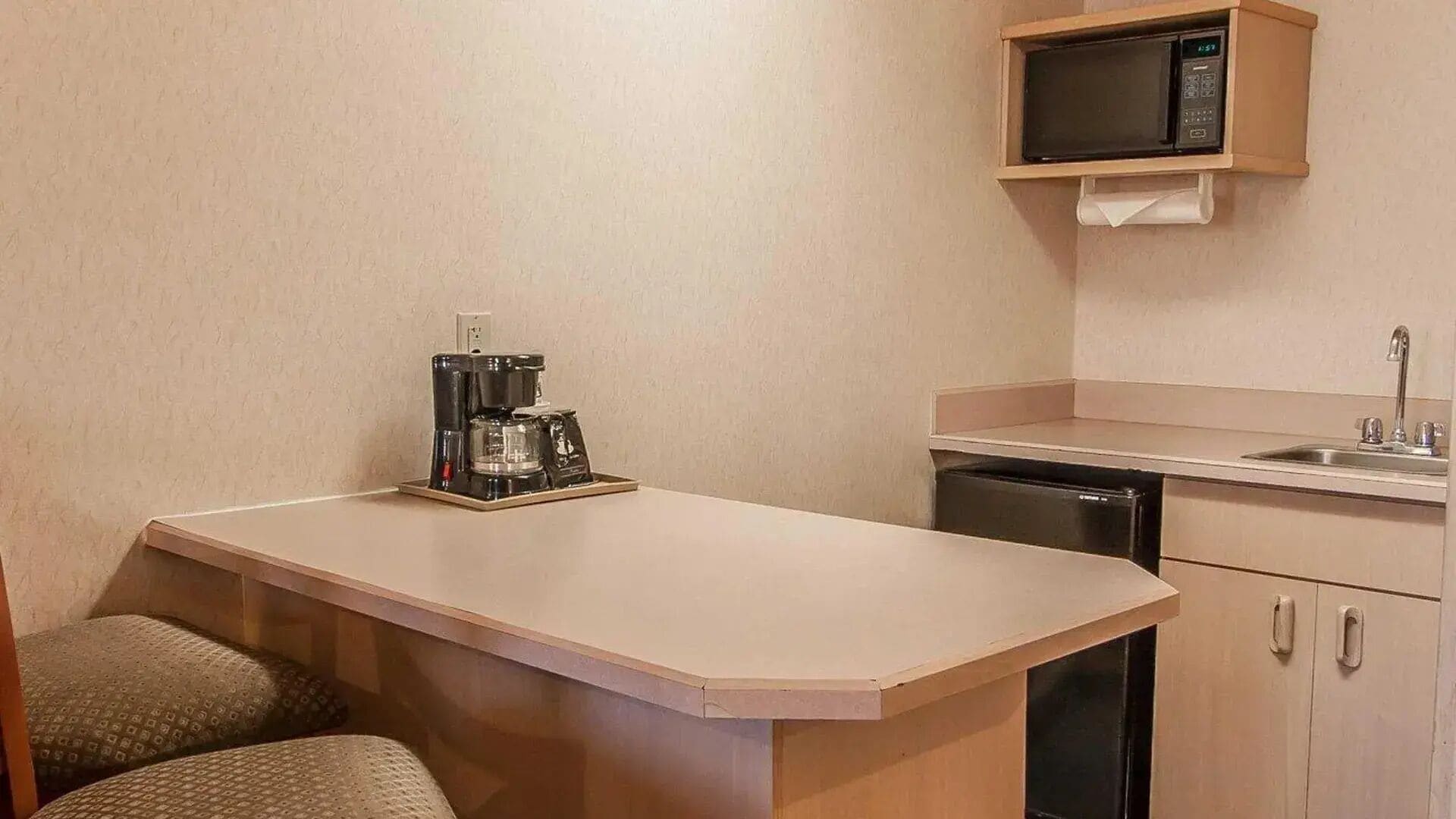 Uma cozinha compacta equipada com cafeteira, micro-ondas e máquina de lavar loiça.