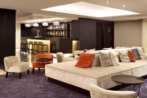 Uma sala de estar moderna com um sofá seccional, um espaço bar com banquetas e uma mesa de jantar.
