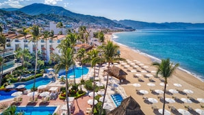 Um resort com piscina, praia e palmeiras.