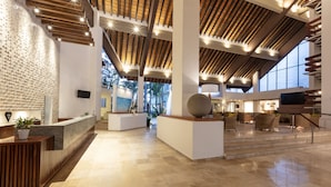 Um hall amplo com teto alto, vigas de madeira e um balcão de recepção.