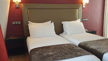 Uma cama de casal com cabeceira, duas mesas de cabeceira e um criado-mudo.