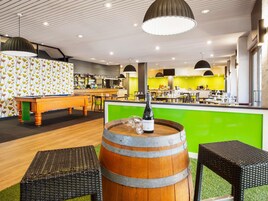 Uma área de bar moderna com mesa de bilhar, banquetas e uma garrafa de vinho sobre um barril.