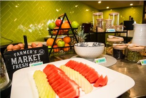 Um buffet de café da manhã com frutas frescas, ovos e diversos acompanhamentos.