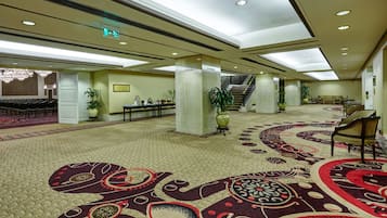 Um hall amplo com carpete estampado, área de estar e escadaria.
