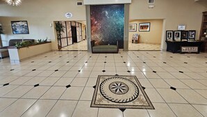Um hall espaçoso com um mural de parede estrelado, uma área de estar central e um chão de azulejos com padrão decorativo.